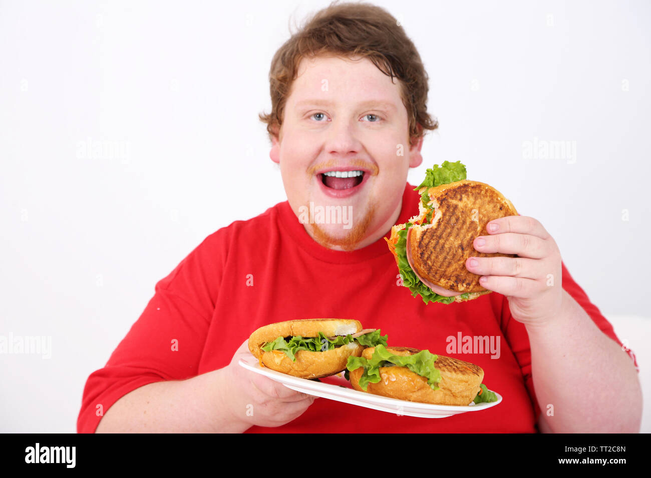 Fat man eating tasty sandwich on home interior background Stock Photo ...