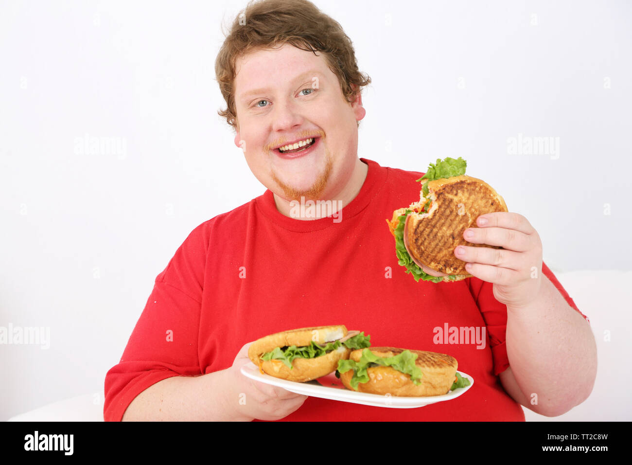 Fat man eating tasty sandwich on home interior background Stock Photo ...