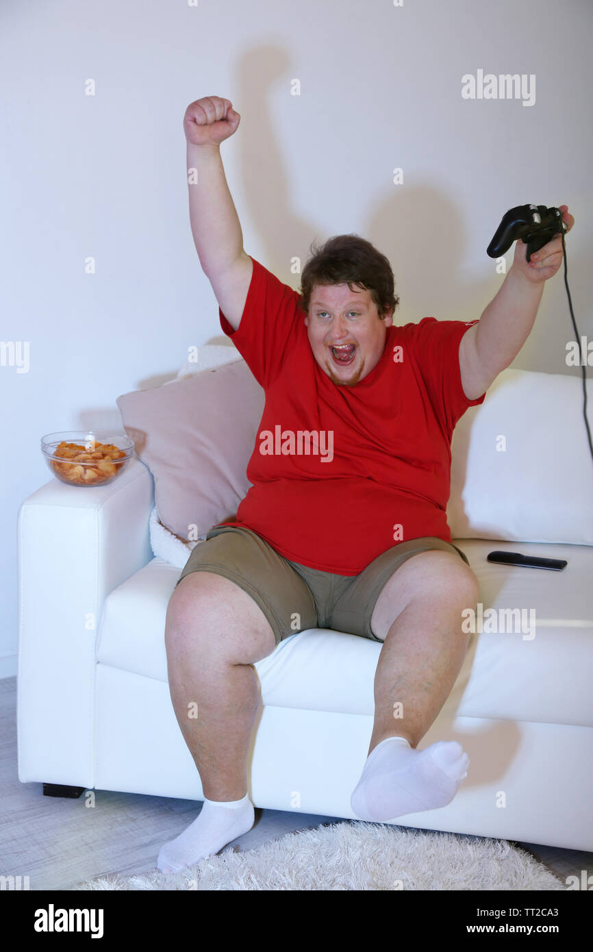 Fat man playing video games on home interior background Stock Photo - Alamy