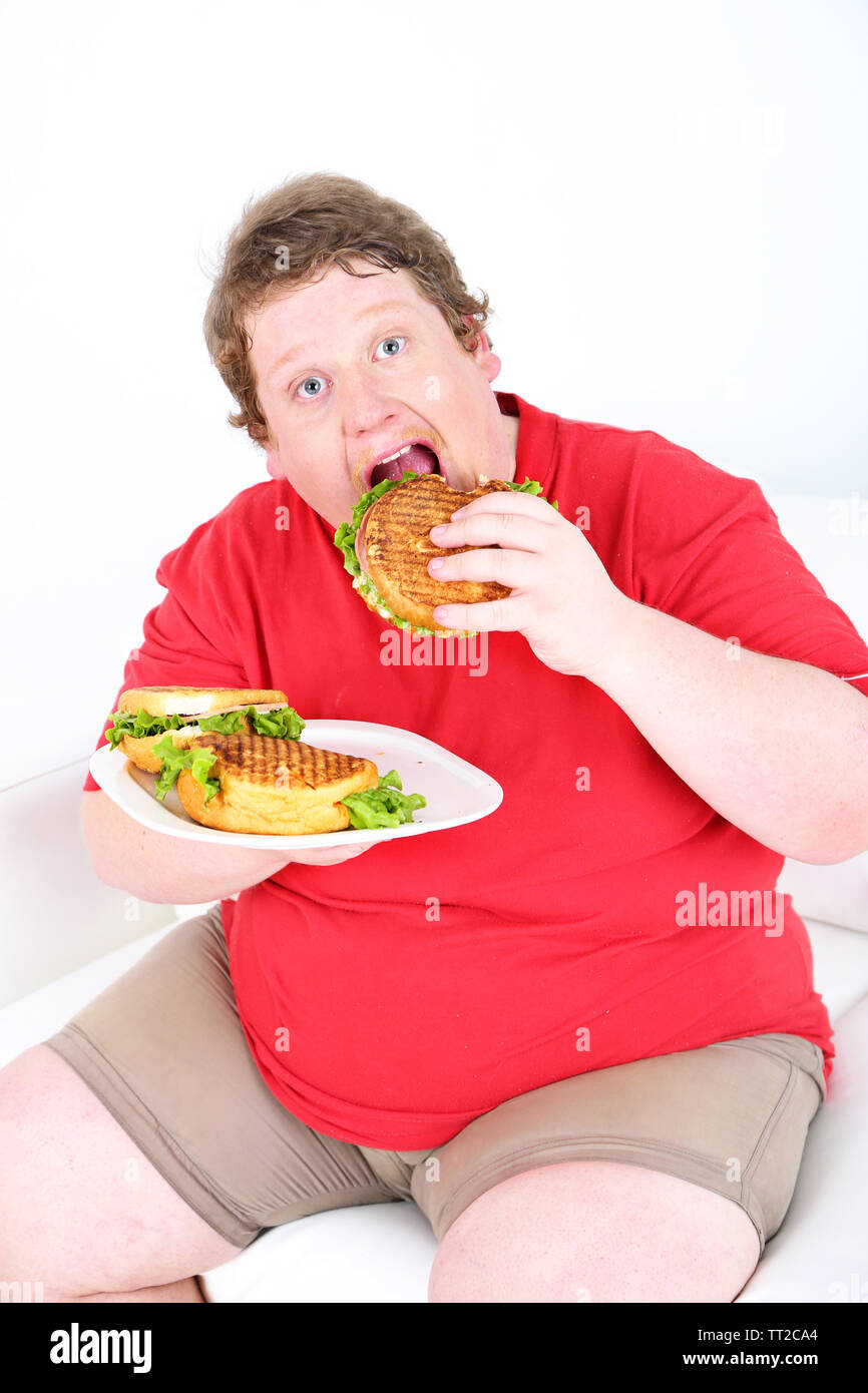 Fat man eating tasty sandwich on home interior background Stock Photo ...