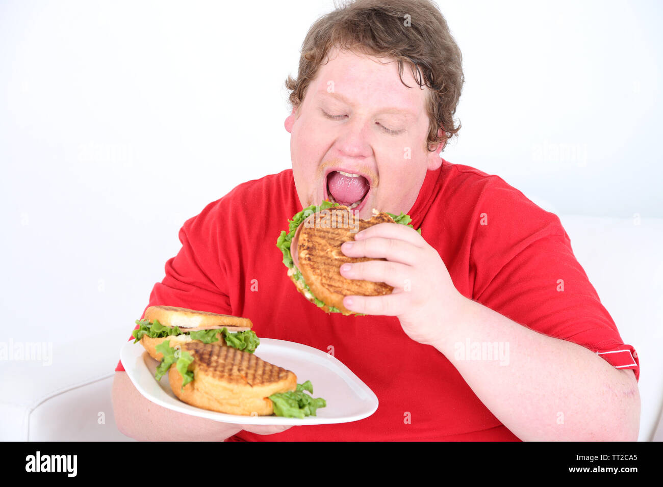 Fat man eating tasty sandwich on home interior background Stock Photo ...