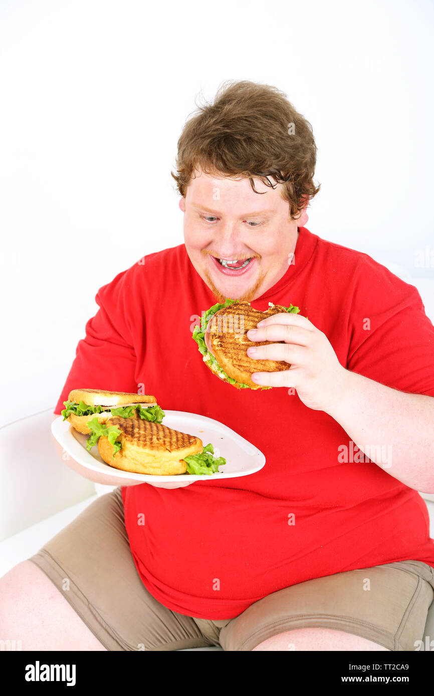 Fat man eating tasty sandwich on home interior background Stock Photo ...