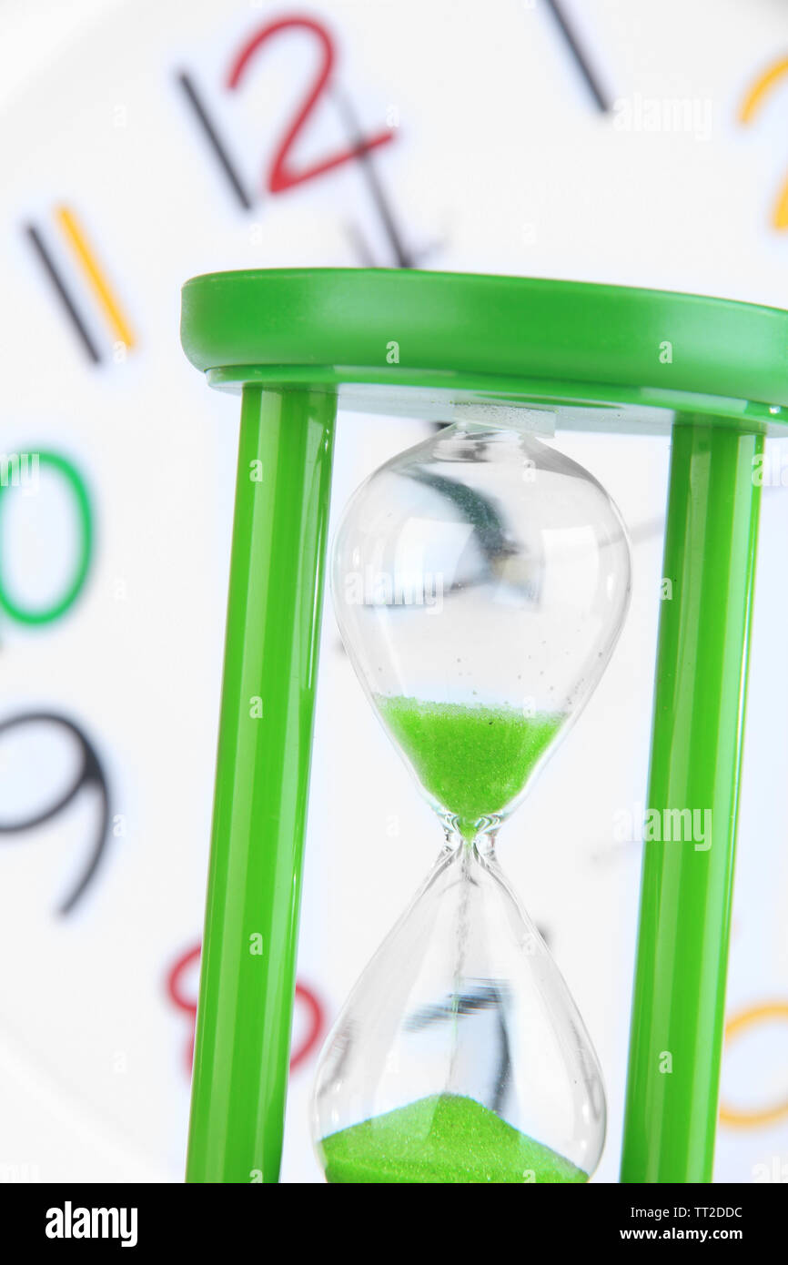Hourglass on big clock background Stock Photo - Alamy