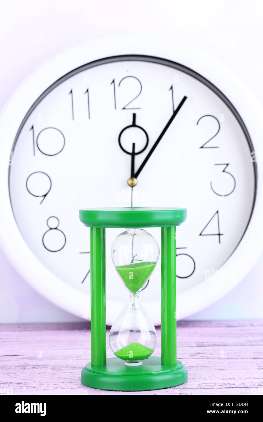 Hourglass and big clock on light background Stock Photo - Alamy