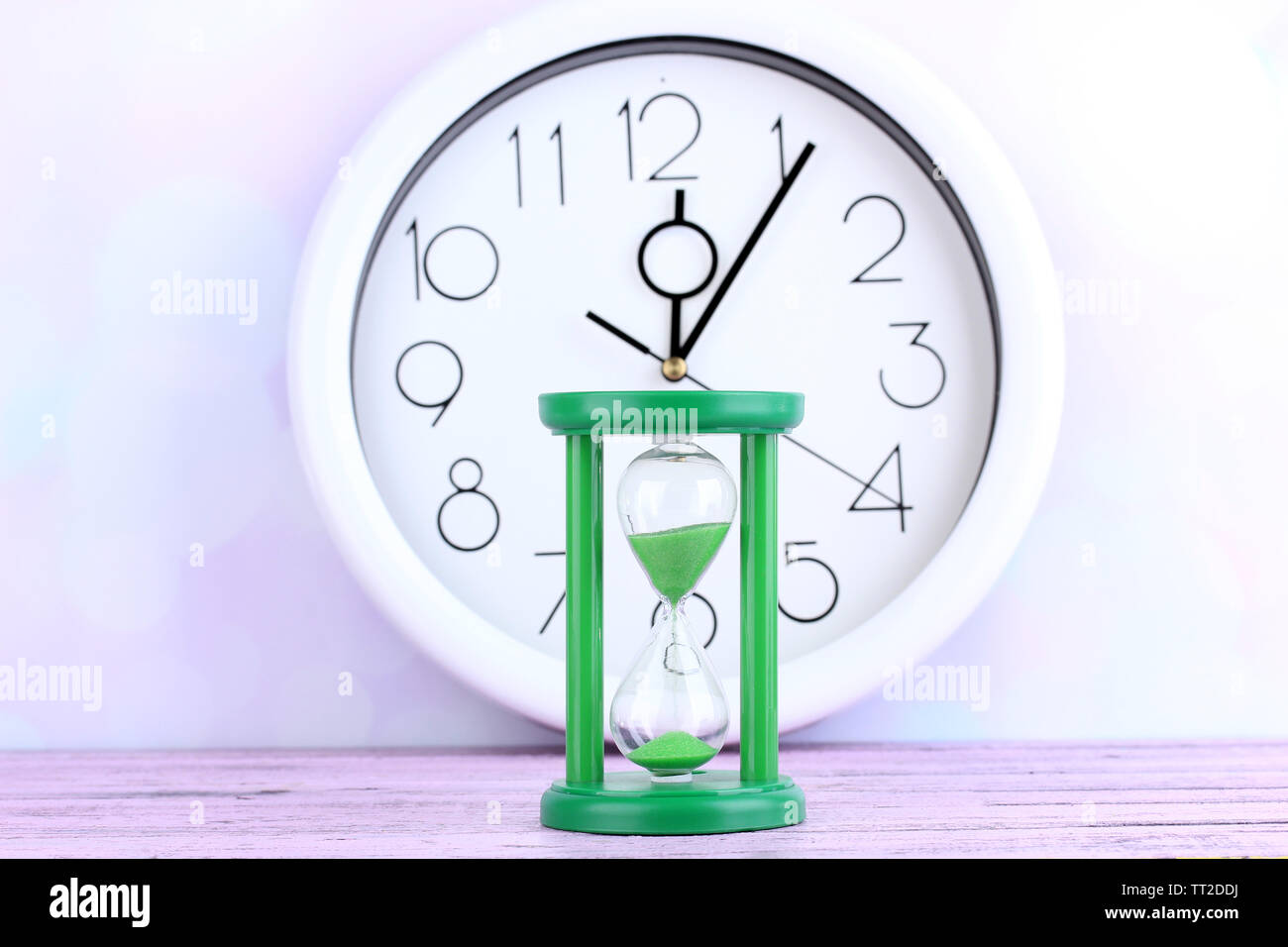 Hourglass and big clock on light background Stock Photo - Alamy
