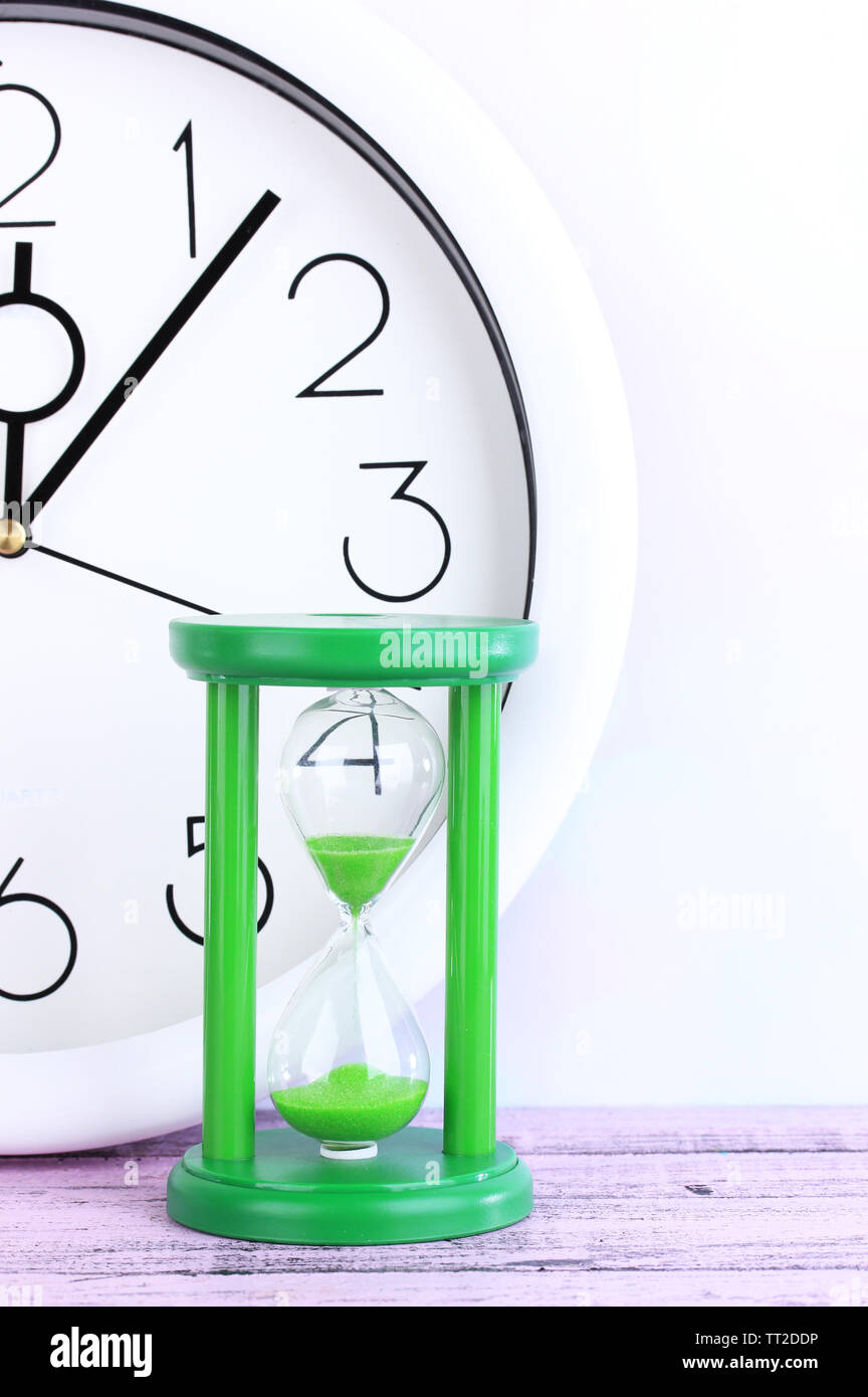 Hourglass and big clock on light background Stock Photo - Alamy