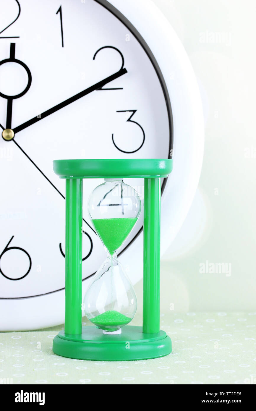 Hourglass and big clock on light background Stock Photo - Alamy