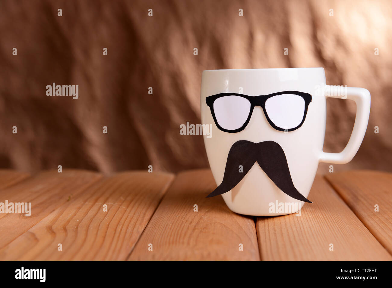 Cup with mustache on table on brown background Stock Photo - Alamy