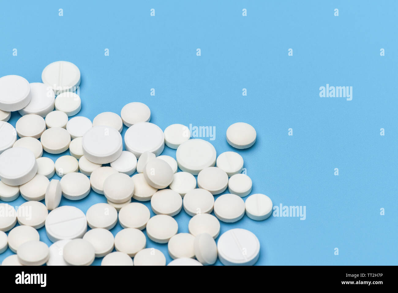 Lots of round white pills on blue background. Medication scattered on a ...