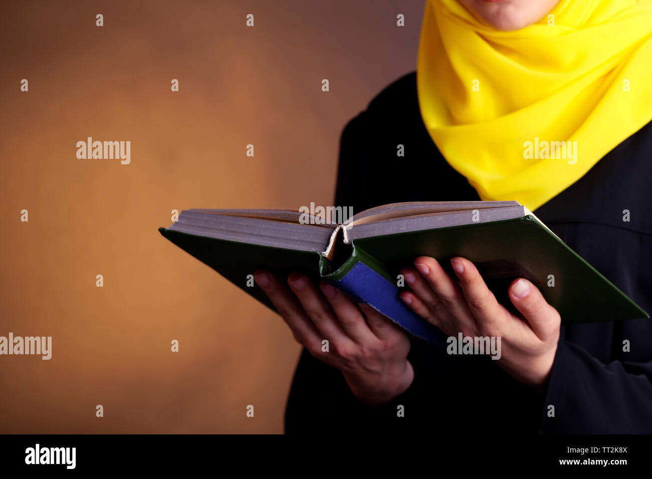 Beautiful muslim arabic woman reading book on dark color background ...