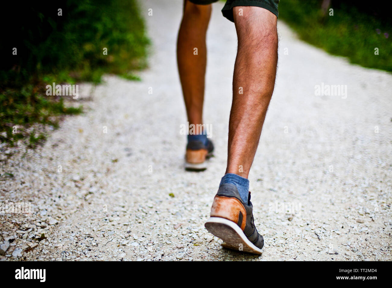 Low angle ground level view with feet of a man on park or forest path ...