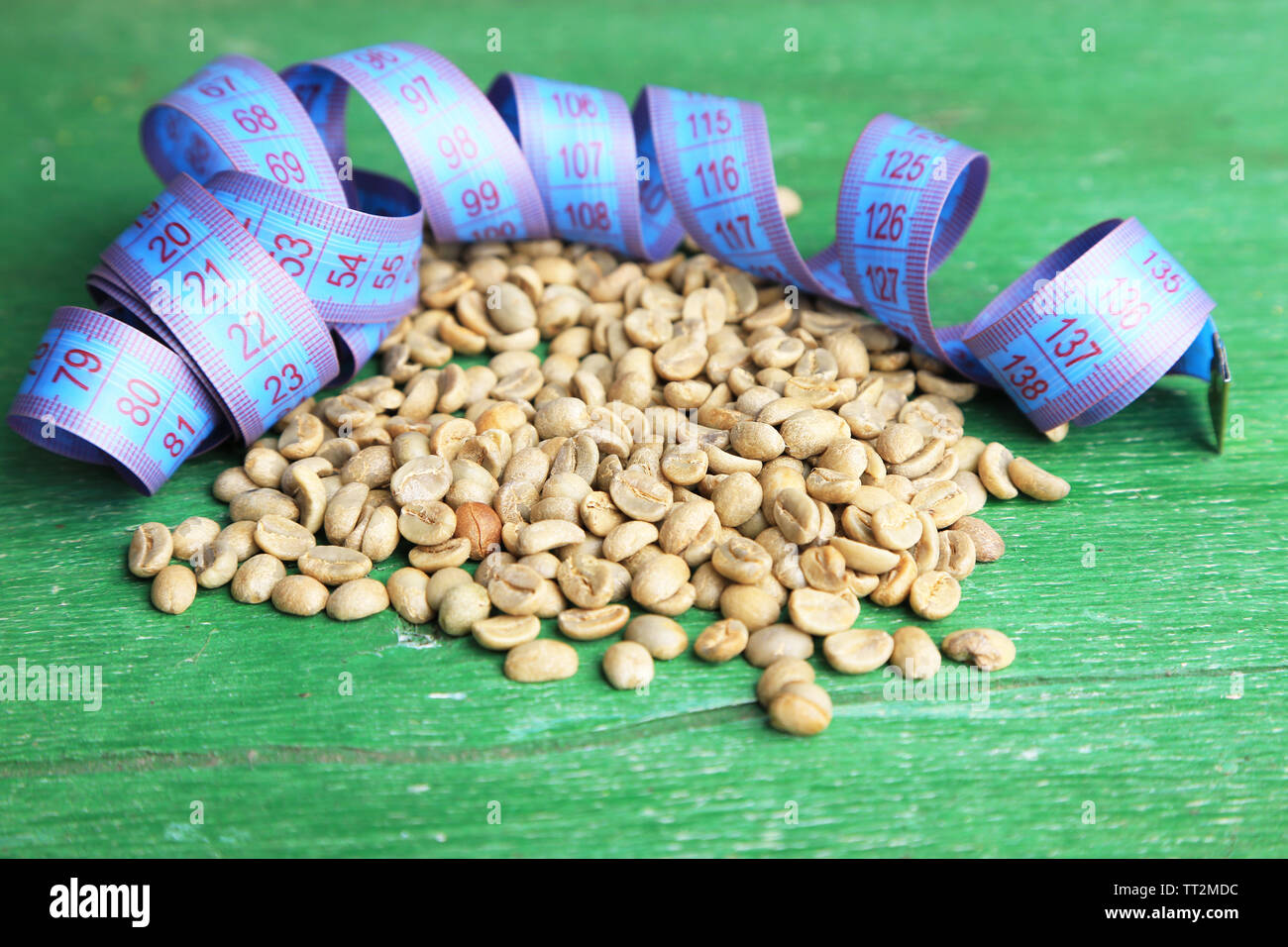 Raw green coffee beans and measuring tape, on color wooden background ...