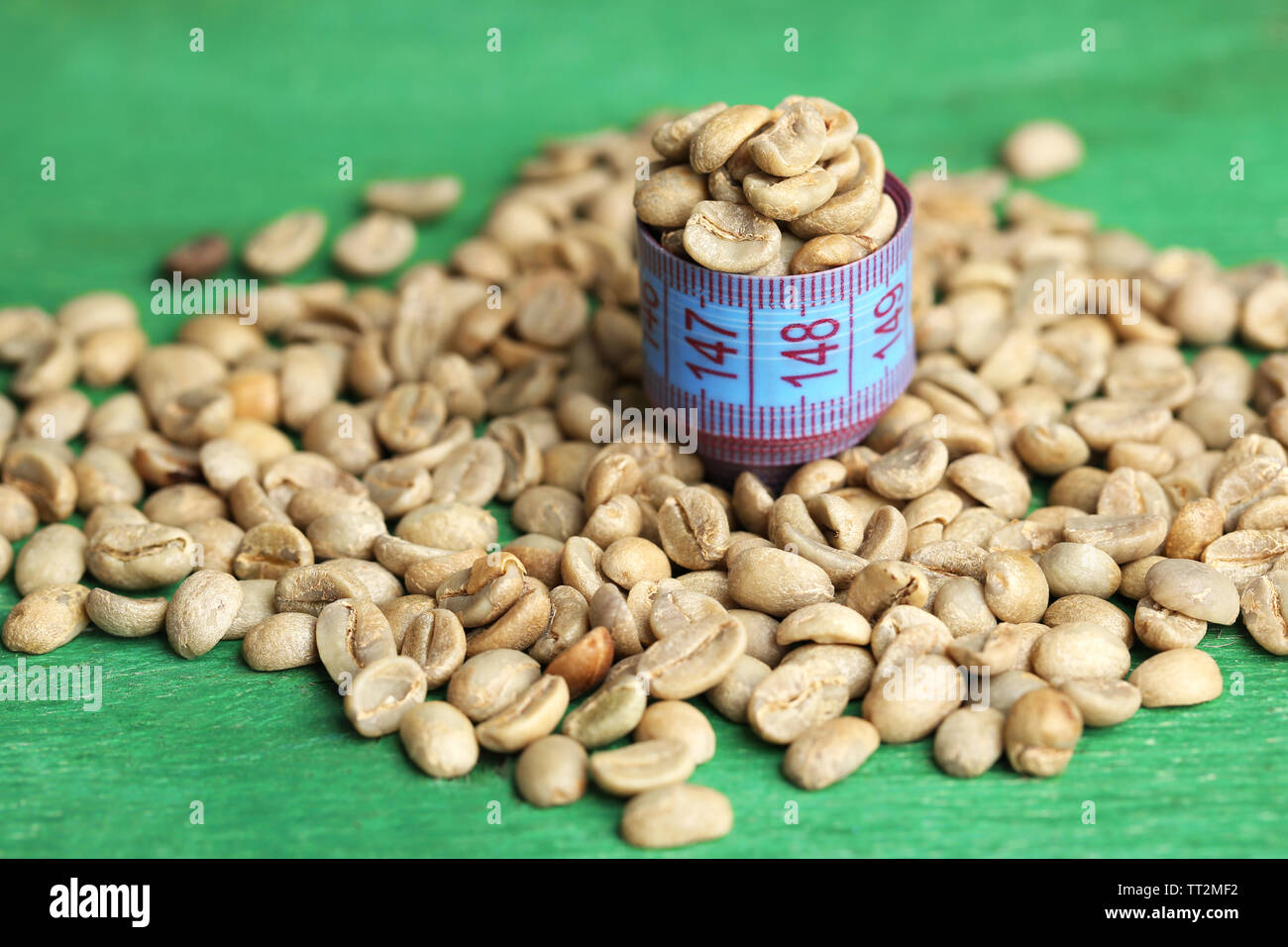 Raw green coffee beans and measuring tape, on color wooden background ...