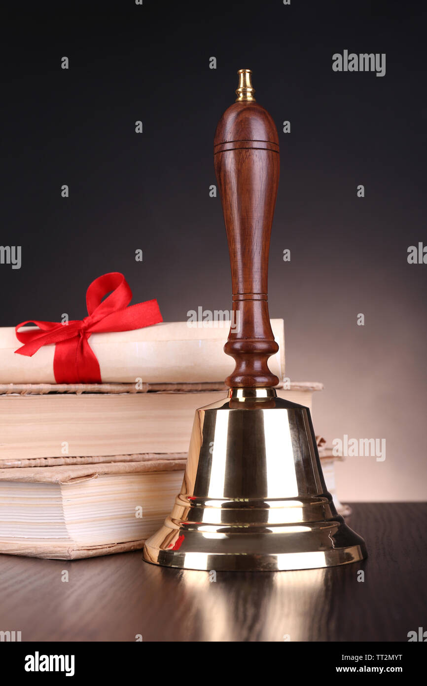 Gold retro school bell with books on table on dark background Stock ...