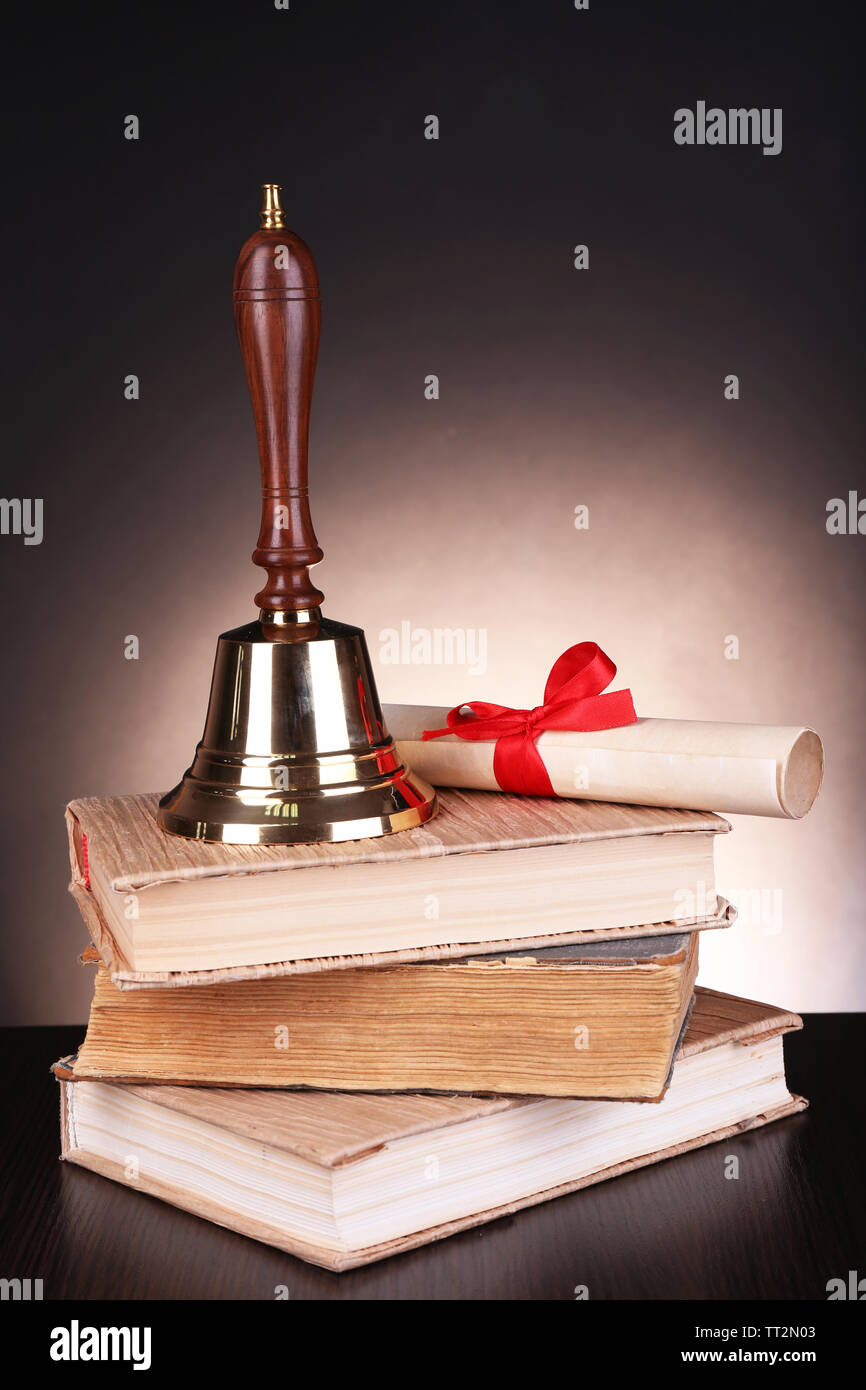 Gold retro school bell with books on table on dark background Stock ...
