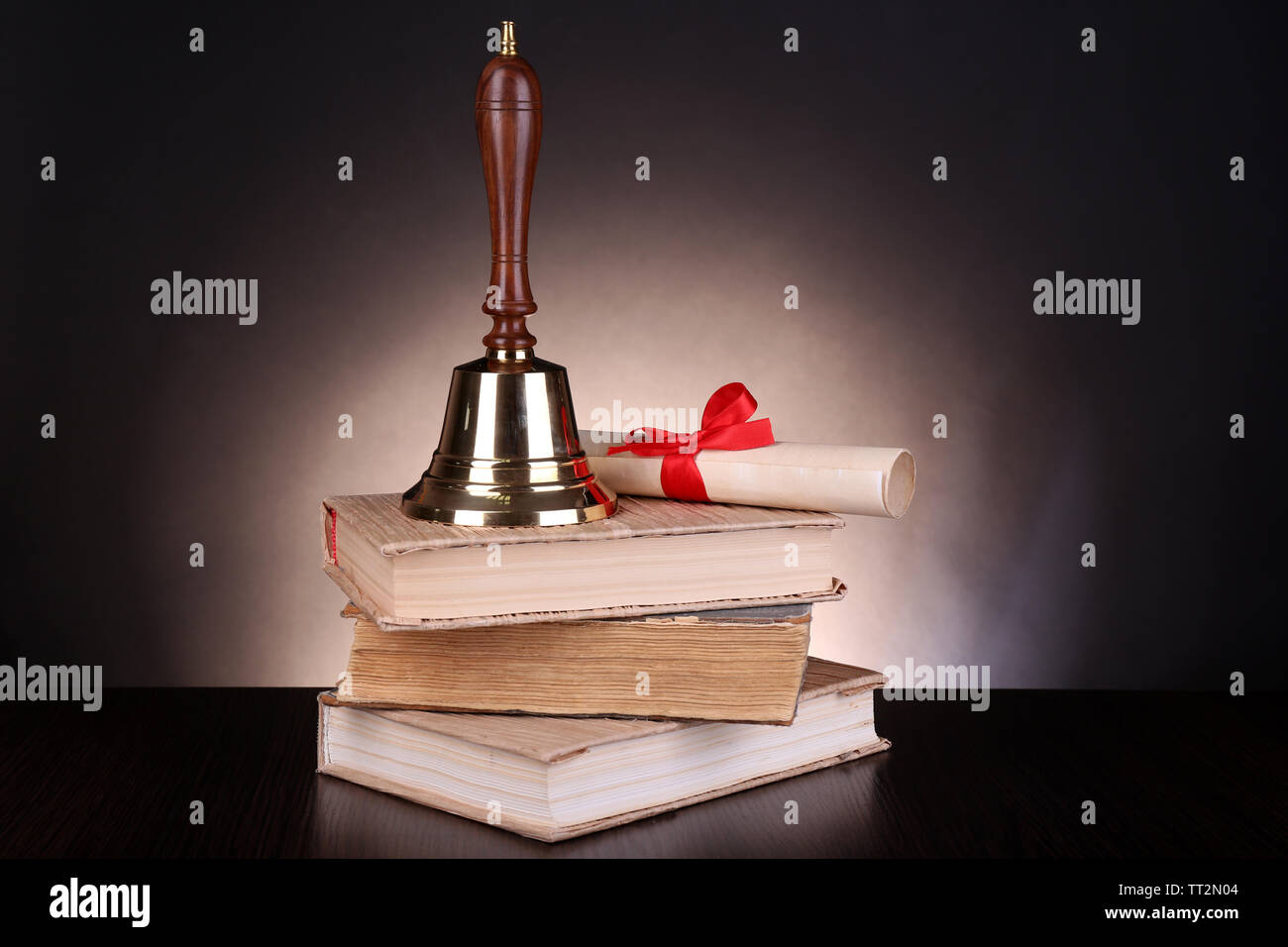 Gold retro school bell with books on table on dark background Stock ...