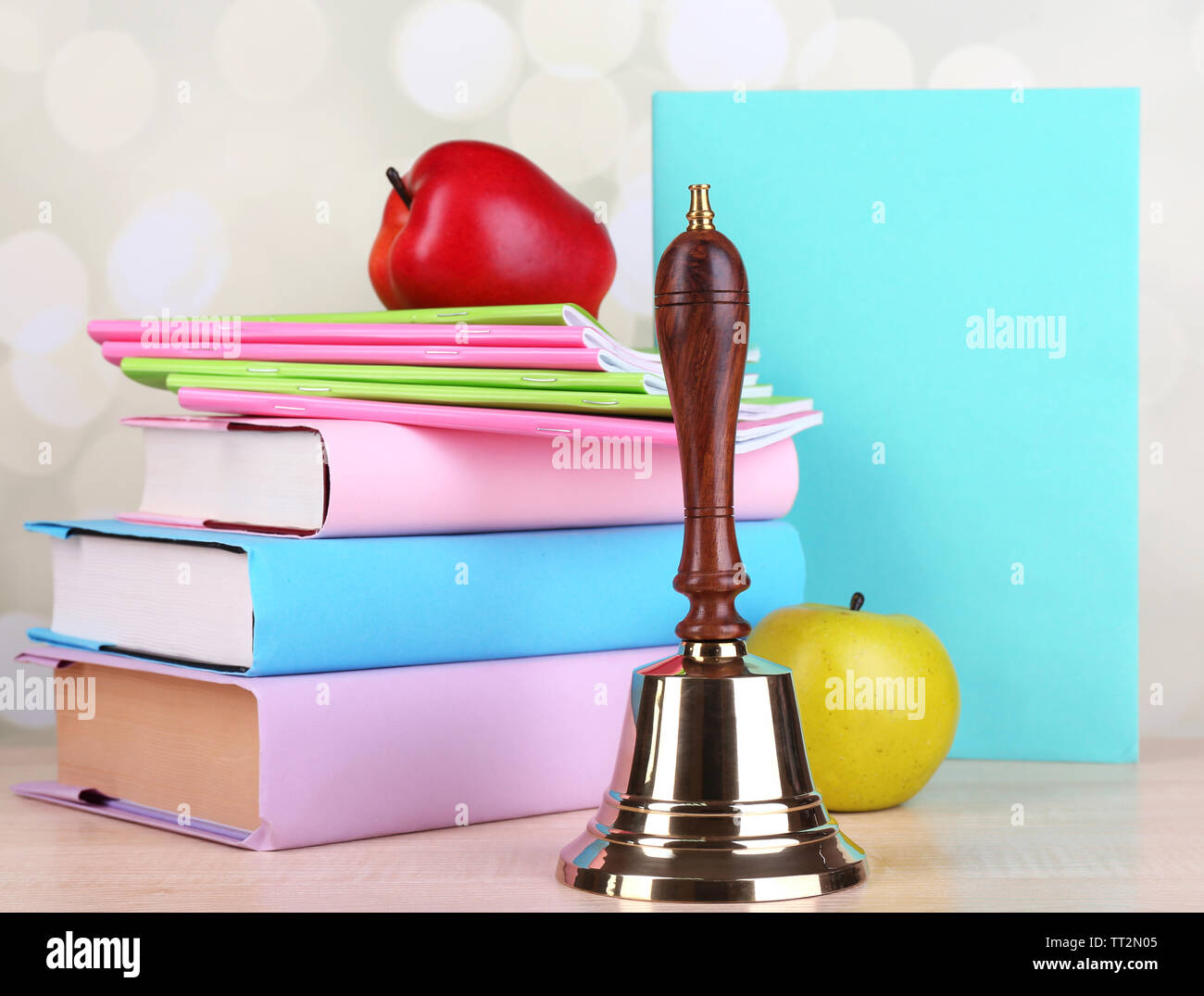Gold school bell with school supplies on table on bright background ...
