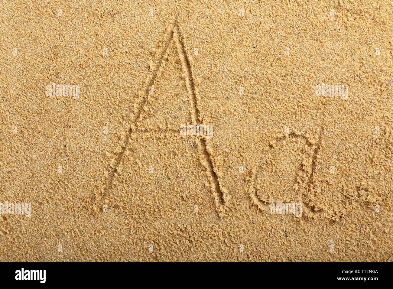 Alphabet letter written on wet beach sand Stock Photo - Alamy