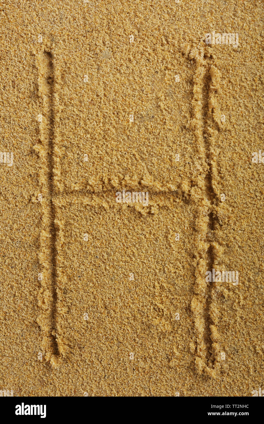 Alphabet letter written on wet beach sand Stock Photo - Alamy