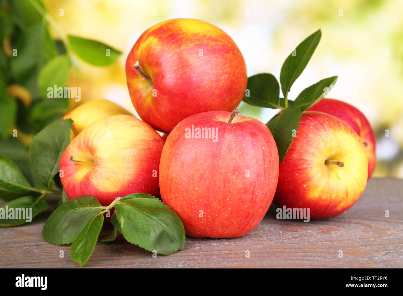 Ripe sweet apples with leaves on nature background Stock Photo - Alamy