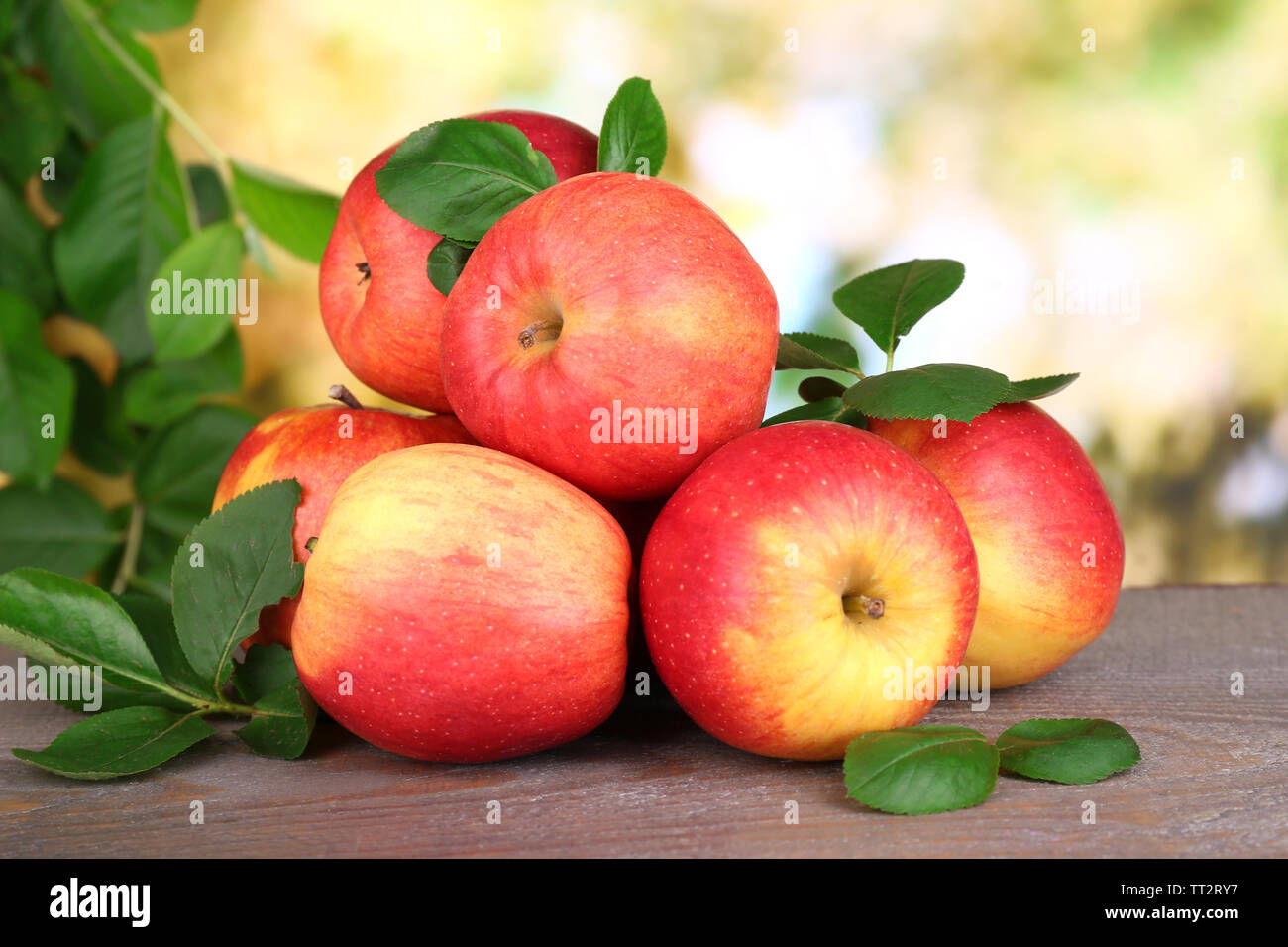 Ripe sweet apples with leaves on nature background Stock Photo - Alamy
