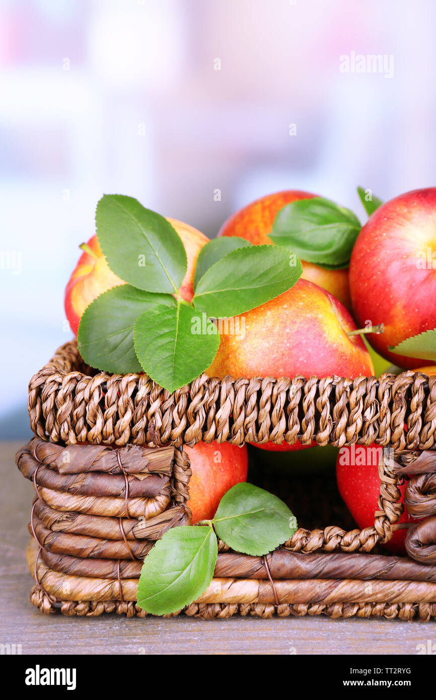 Ripe sweet apples with leaves in wicker crate on light background Stock ...