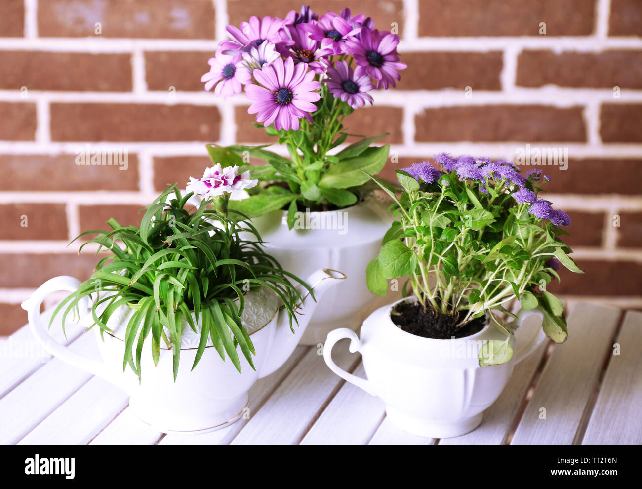 Flowers in decorative pots on table, on bricks background Stock Photo ...