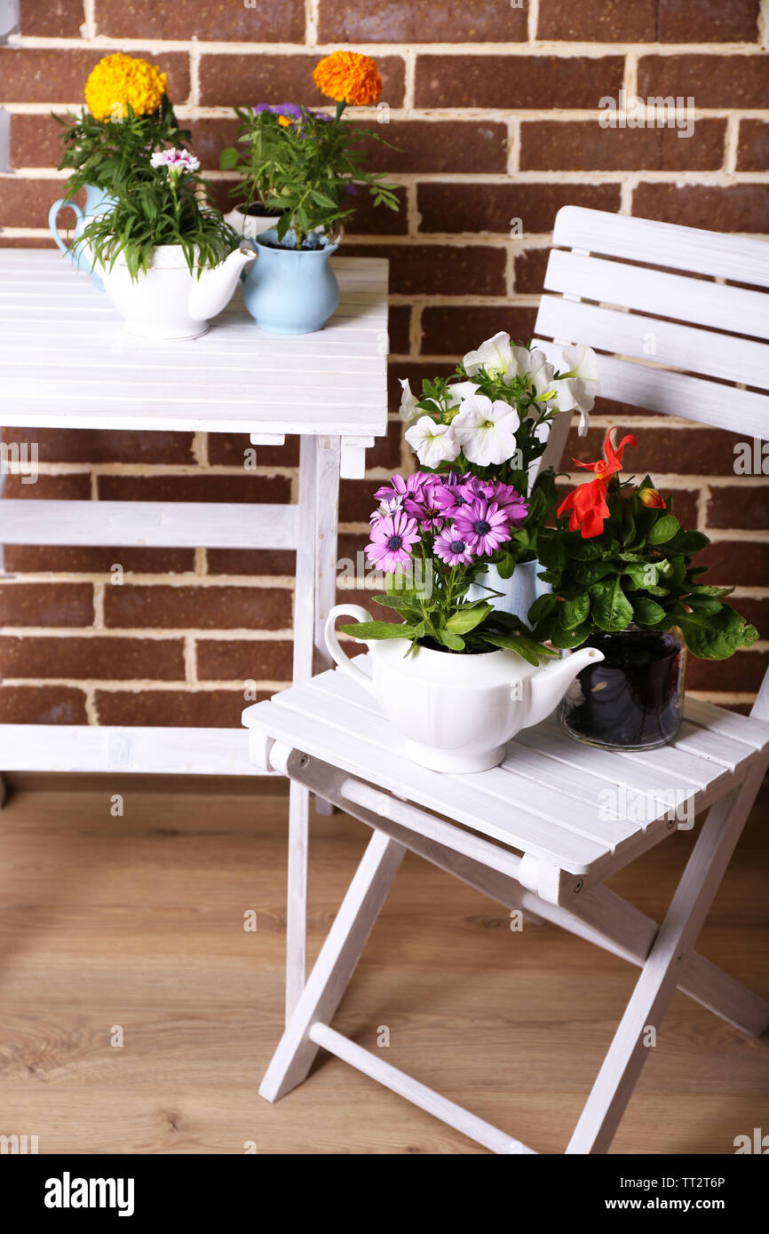 Flowers in decorative pots on table, on bricks background Stock Photo ...