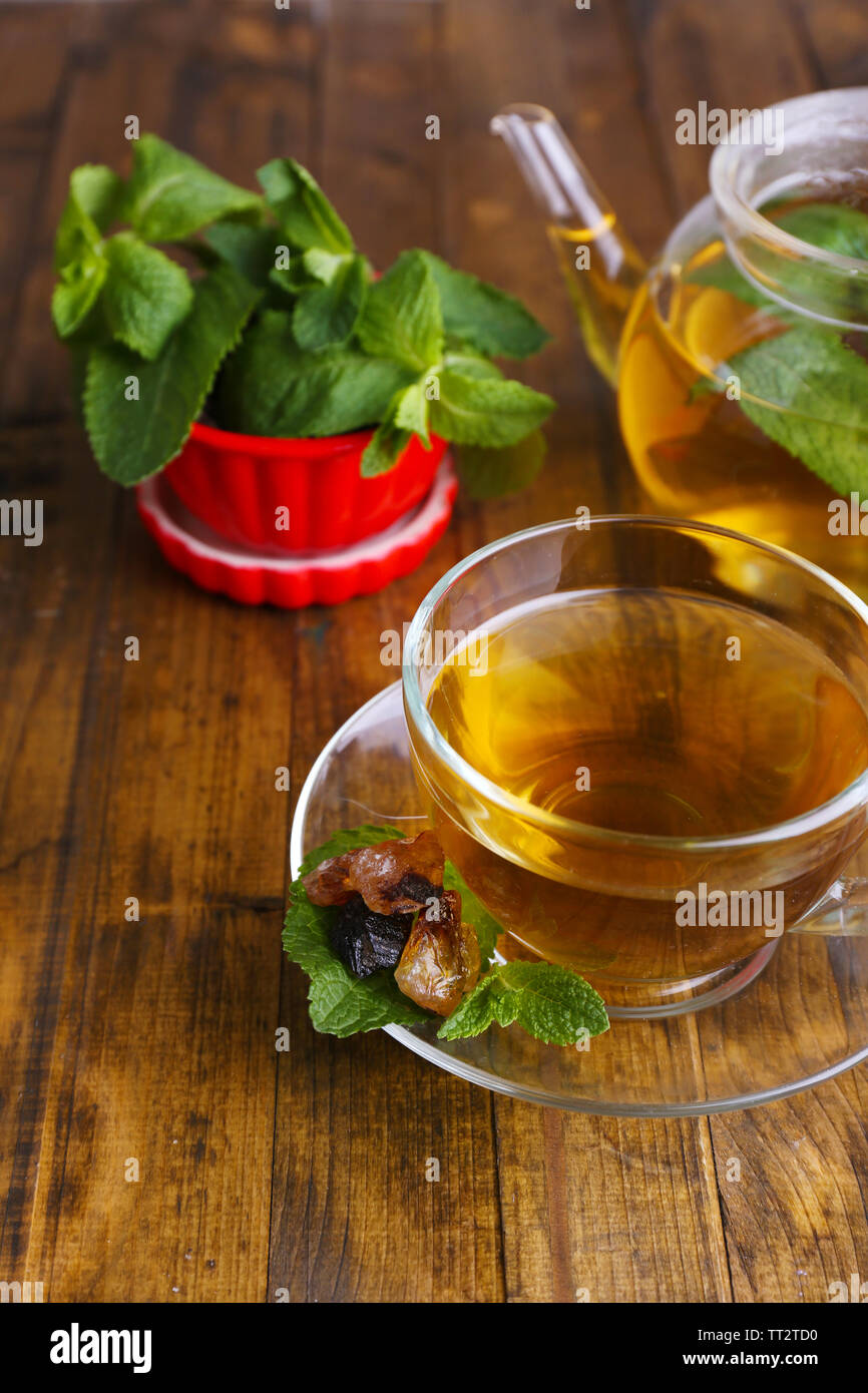 Composition of fresh mint tea in glass cup and teapot on wooden ...