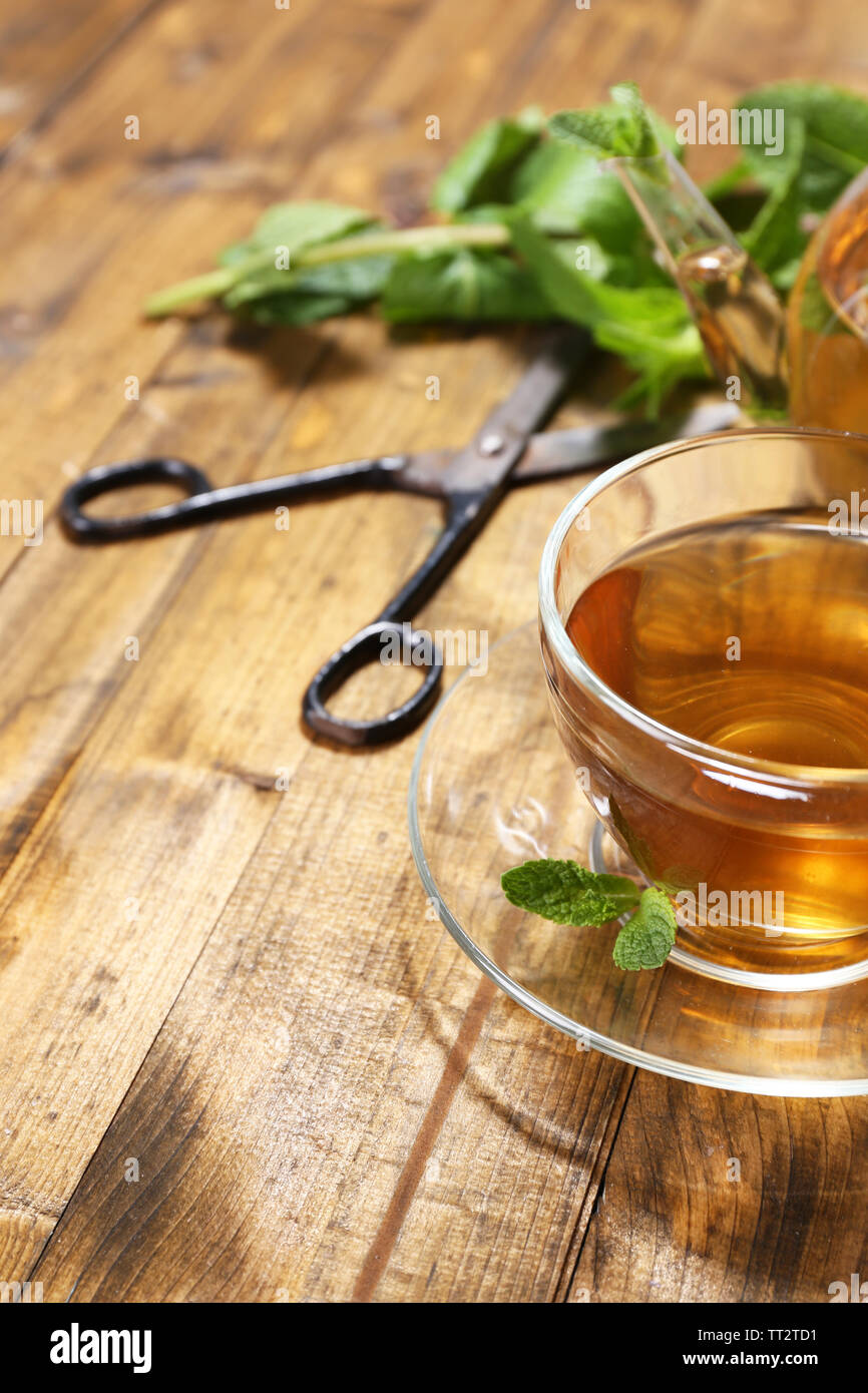 Composition of fresh mint tea in glass cup and teapot on wooden ...