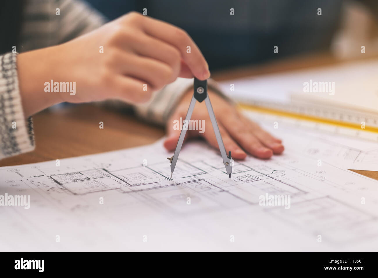 An architect using compass to draw and measure shop drawing in office ...