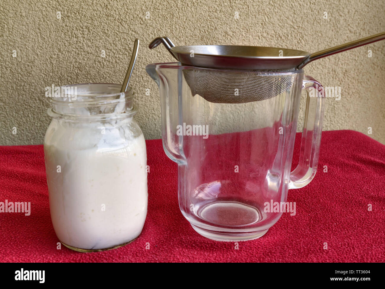 Pouring of Kefir, the glass jar is placed next to the net to pour the ...