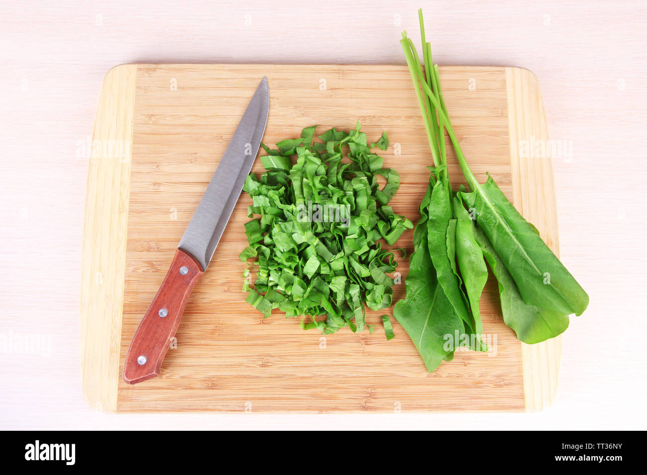 Chopped greens with knife on cutting board on table Stock Photo - Alamy