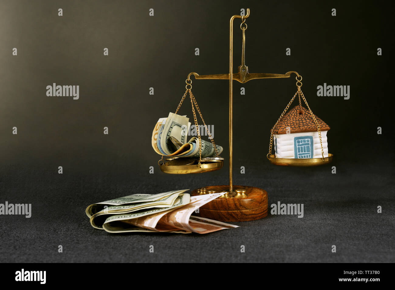 Scale with money and model of house on dark background Stock Photo - Alamy
