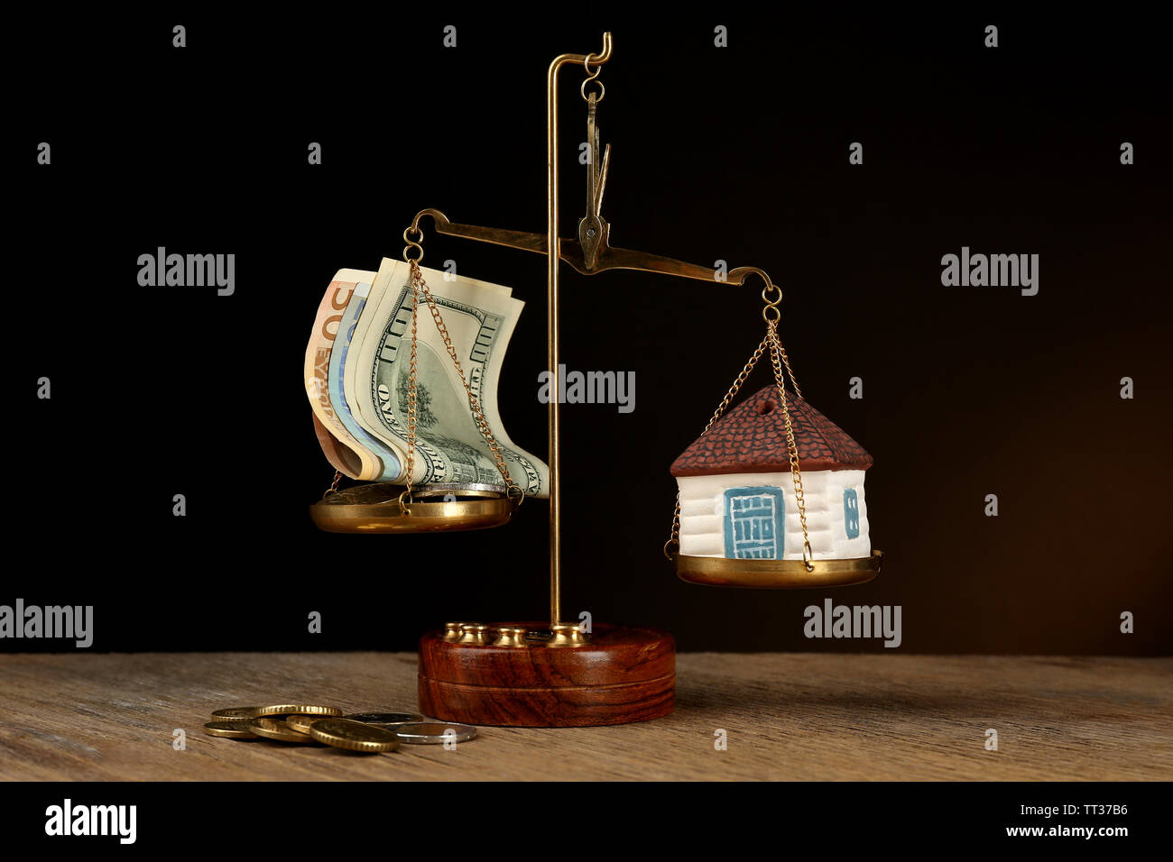 Scale with money and model of house on dark background Stock Photo - Alamy