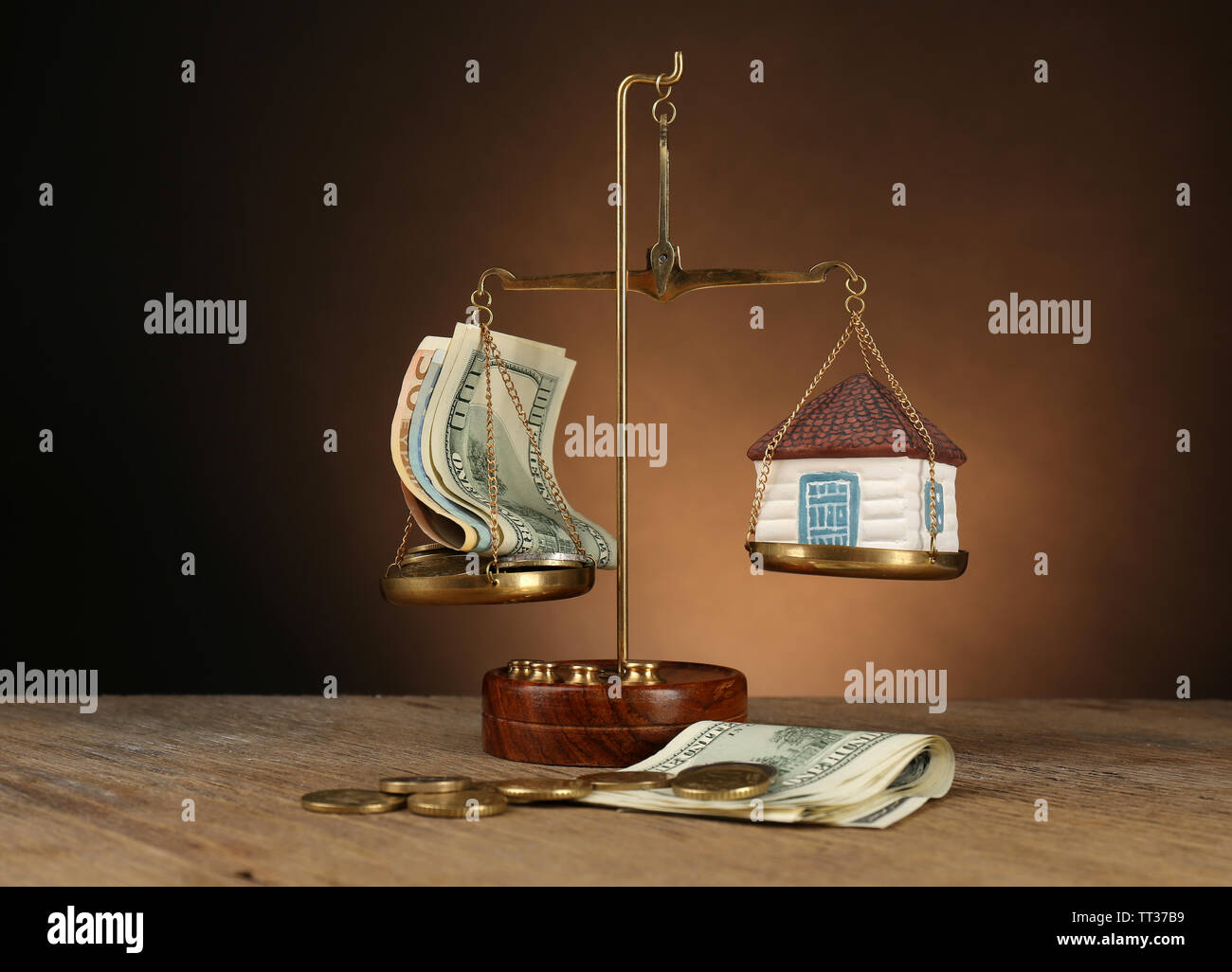Scale with money and model of house on dark background Stock Photo - Alamy