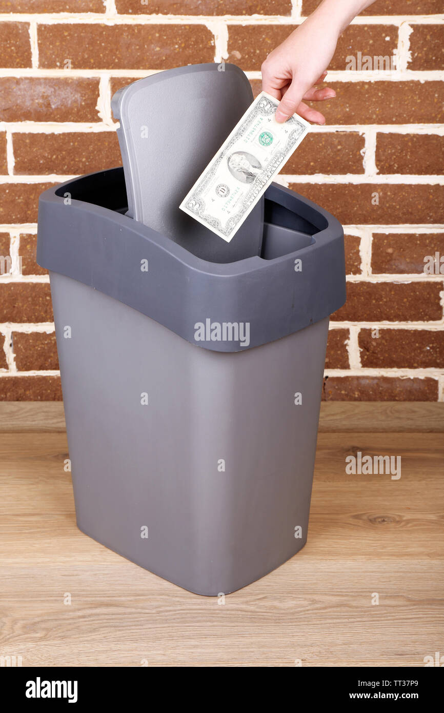 Throwing away your money on brick wall background Stock Photo - Alamy