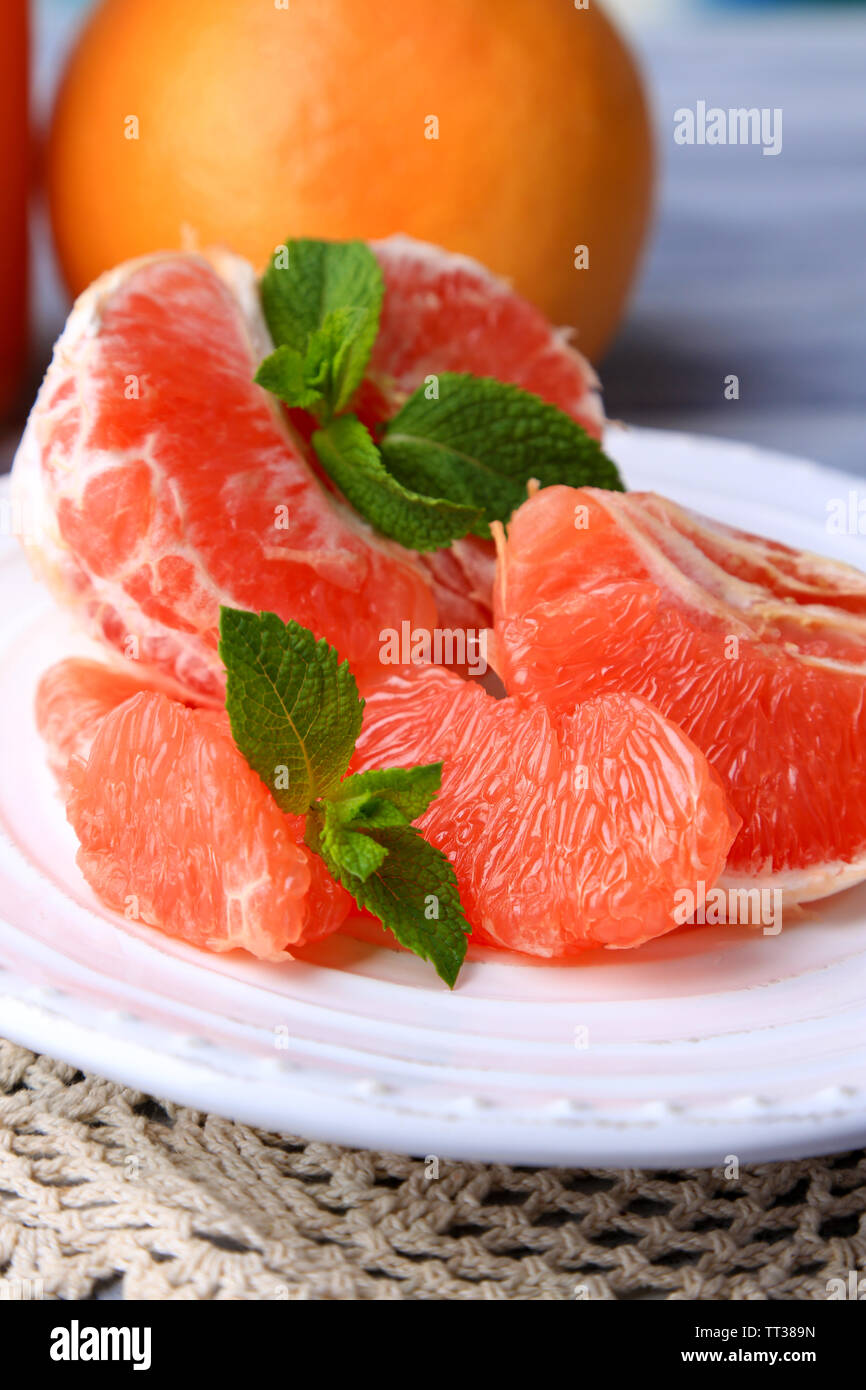 Ripe peeled grapefruits on plate, on color wooden table, on light ...