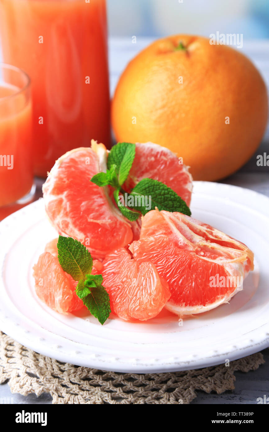 Ripe peeled grapefruits on plate, on color wooden table, on light ...
