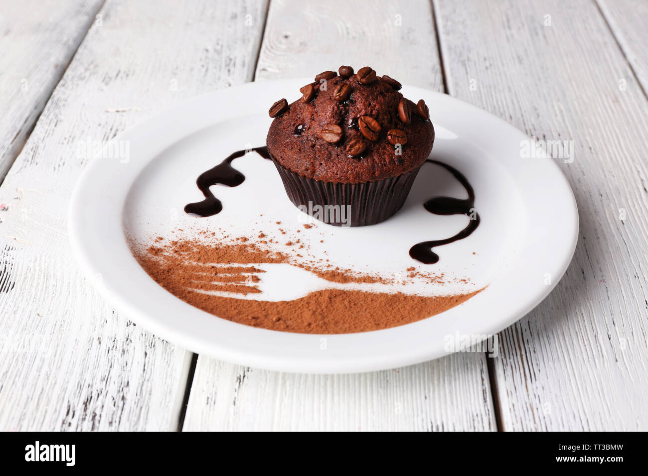 Chocolate muffin with chocolate sauce on plate, on wooden background ...