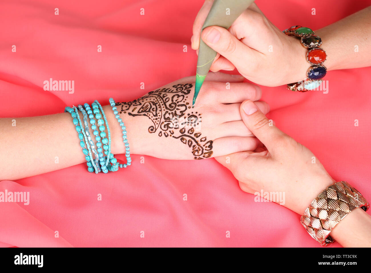 Process of applying Mehndi on female hand on color cloth background ...
