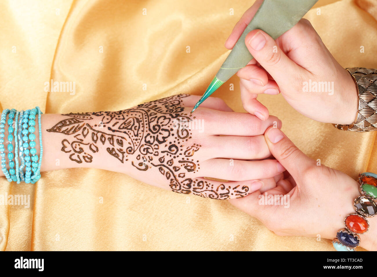 Process of applying Mehndi on female hand on color cloth background ...