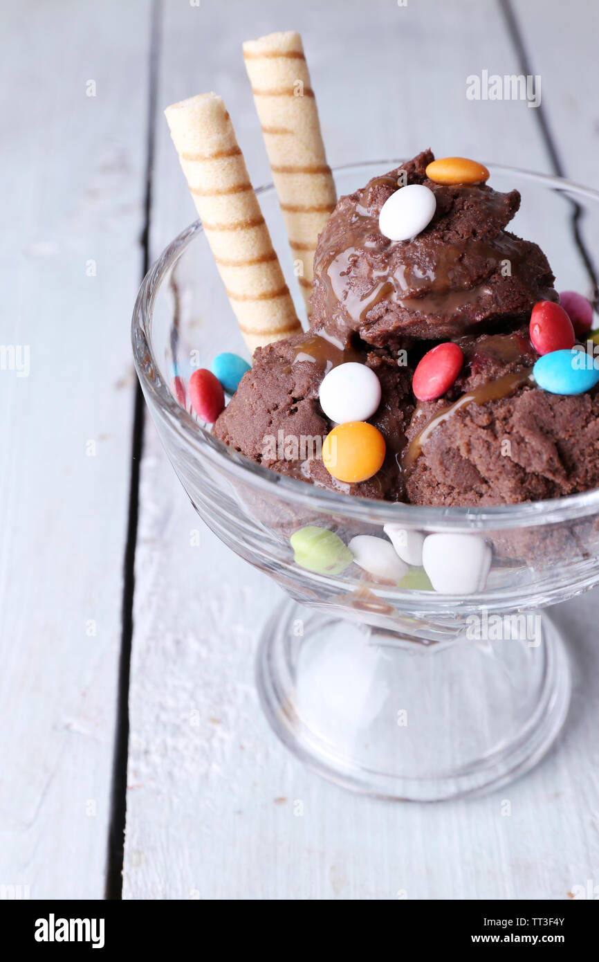Chocolate ice cream with multicolor candies and wafer rolls in glass ...