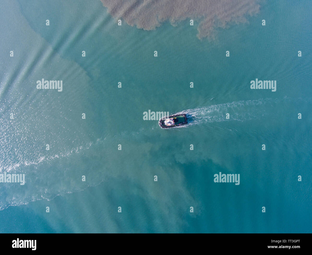 Aerial top view of motion tugboat at azure water with a spot of oil ...