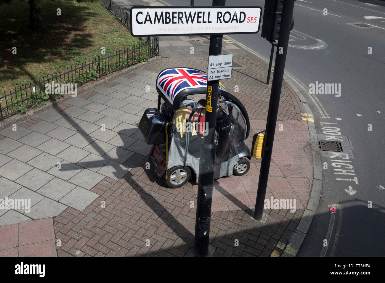 A disabled person drives her mobility scooter on the pavement on the ...