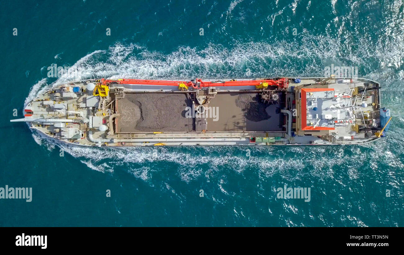 Red Trailing Suction Hopper-Dredger ship roaring across the sea, Aerial ...