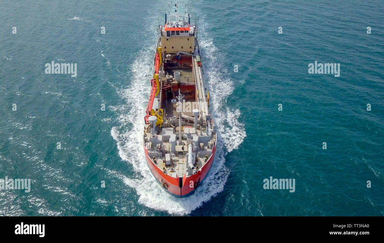 Red Trailing Suction Hopper-Dredger ship roaring across the sea, Aerial ...