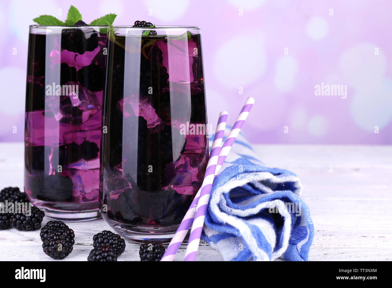 Tasty cool blackberry lemonade with ice on wooden table, on light ...
