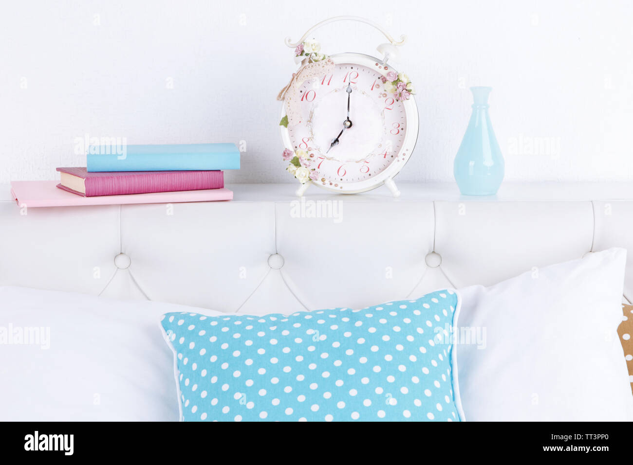 Metal clock on pillows on a big white bed Stock Photo - Alamy