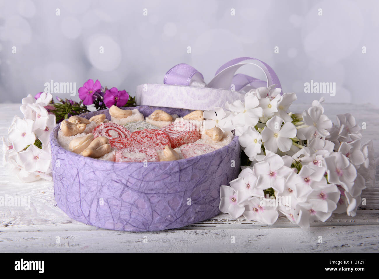 Present box with sweets and flowers on table on bright background Stock ...
